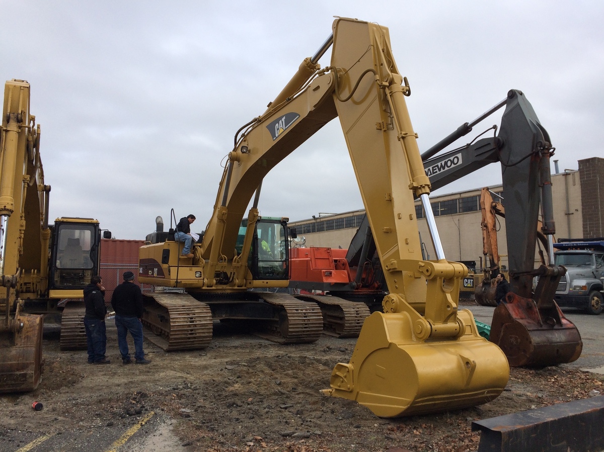 Construction workers bid at an auction for a 345C L Excavator digging ...
